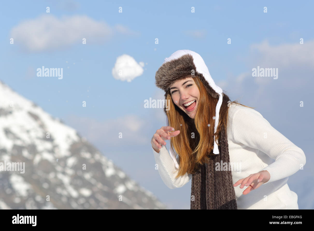 Playful woman throwing a snow ball in winter on holidays in a snowy ...