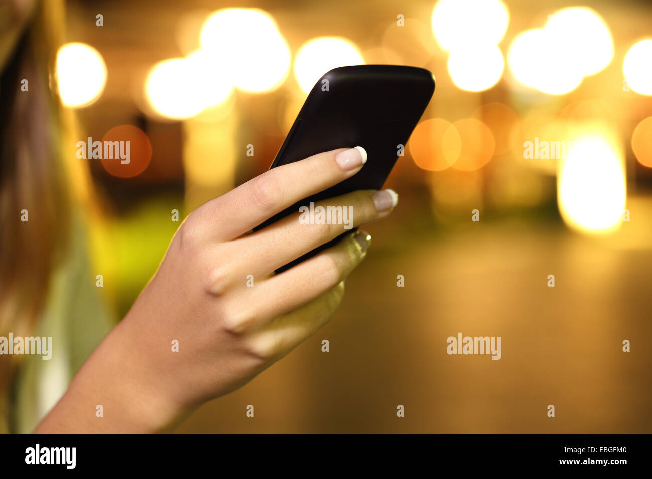 Close up of a woman hand using a smart phone in the night with lights ...