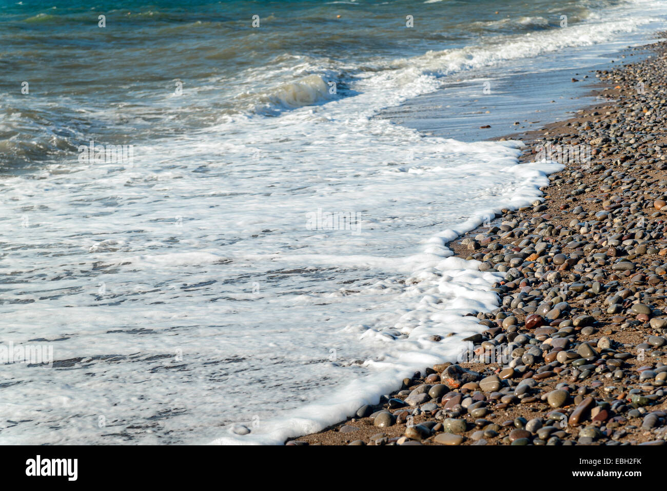 Beach, sea pebbles and sand washed by the waves at sunrise Stock Photo ...