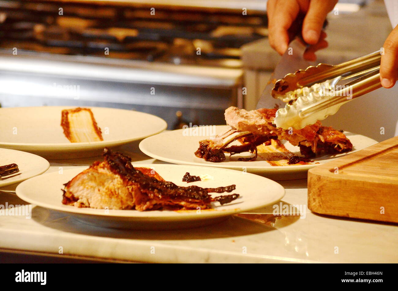Chef's hands cutting and serving wild boar ribs with barbecue sauce ...