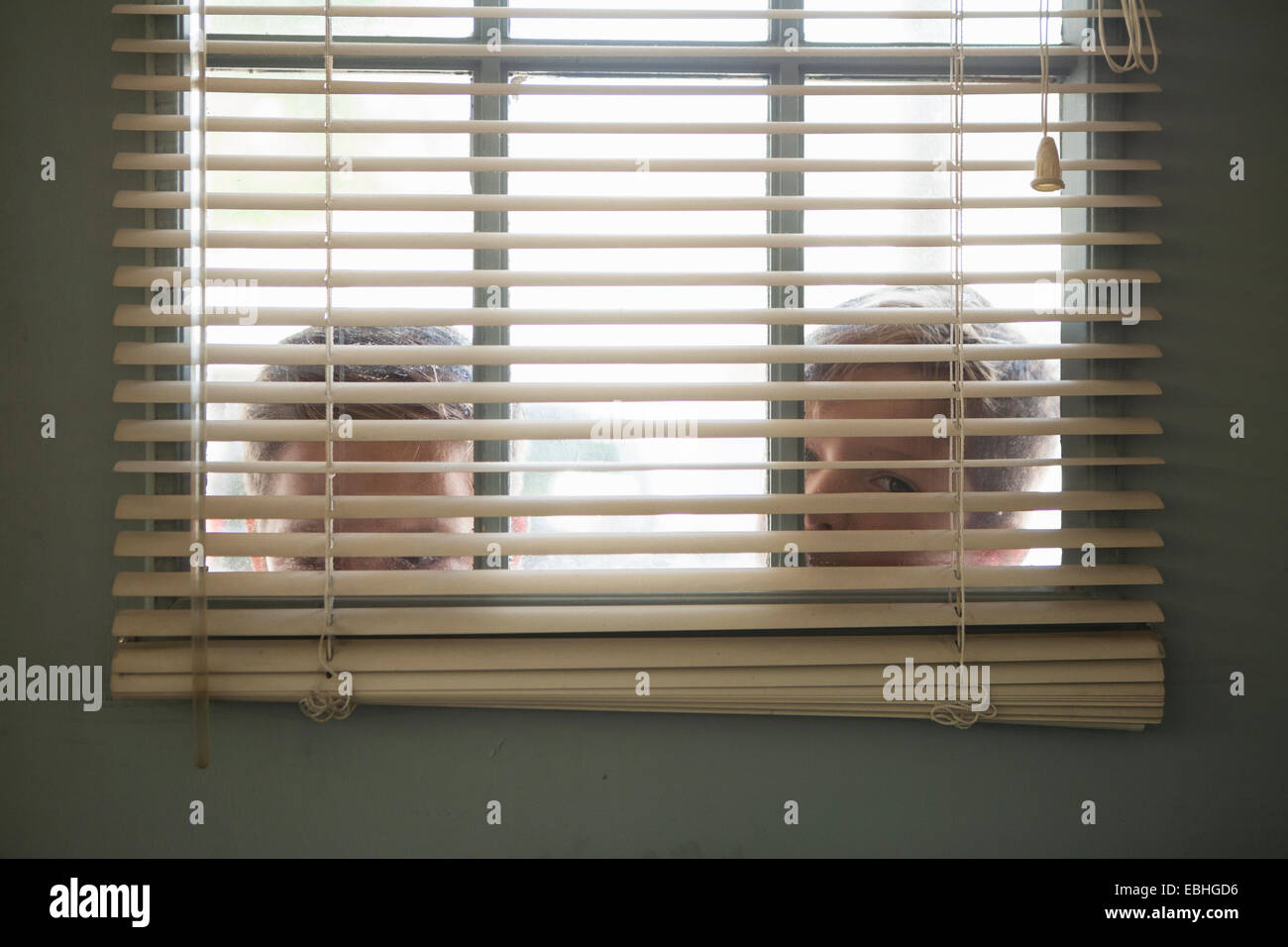Two boys peering through window with venetian blind Stock Photo - Alamy