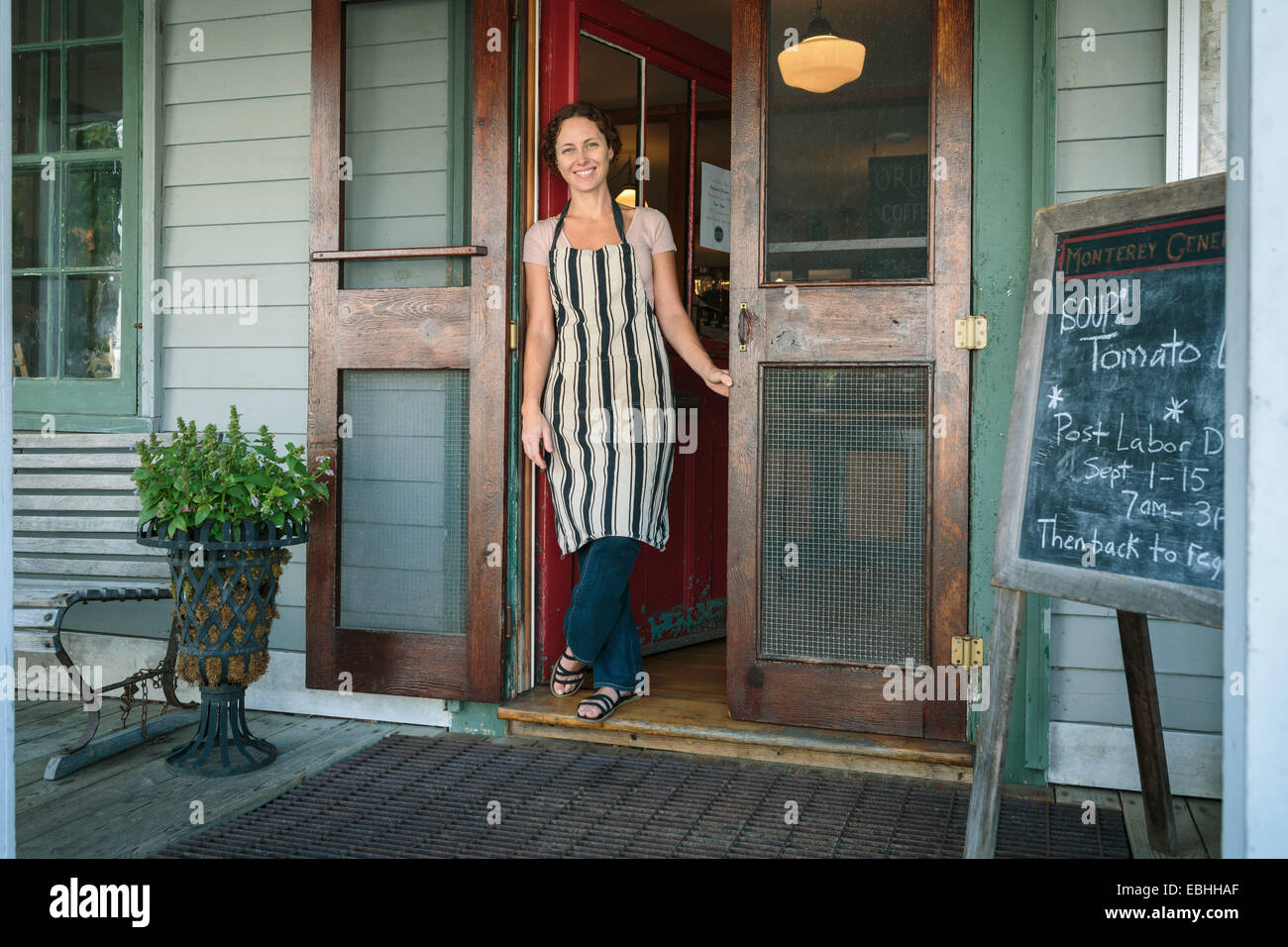 Female shop assistant in doorway of country store Stock Photo - Alamy