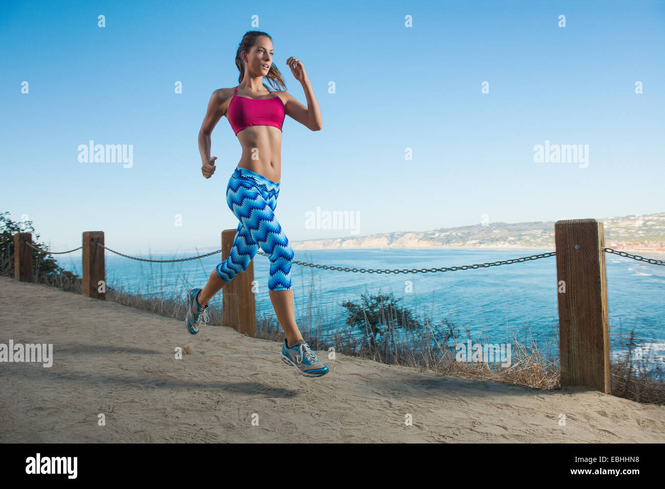 Young woman running on path by sea Stock Photo - Alamy
