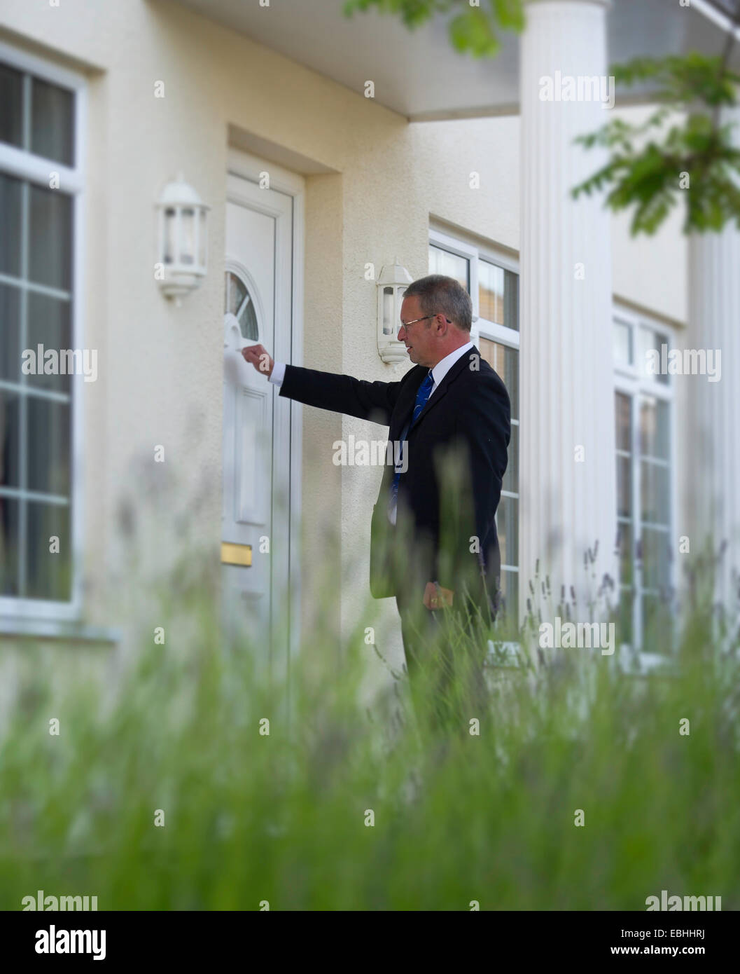A man knocking on a door wearing a suit and tie Stock Photo - Alamy