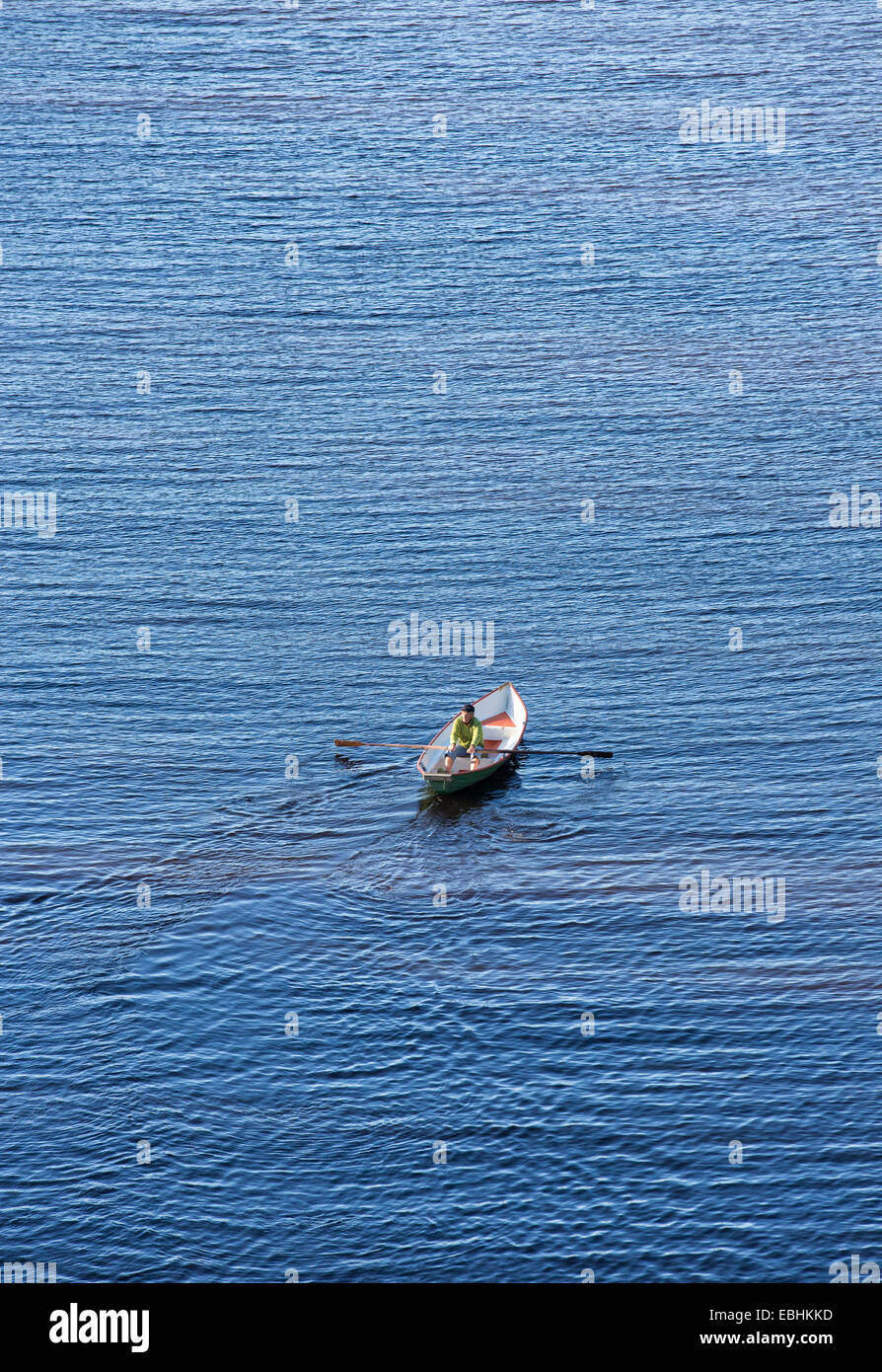 Aerial view of an elderly man rowing a fiberglass rowboat / skiff ...