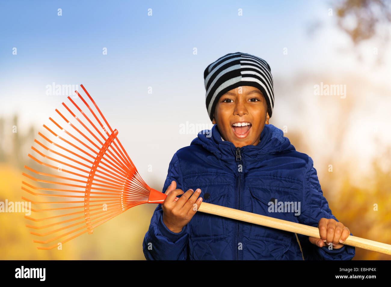 African smiling boy holds red rake with emotions Stock Photo - Alamy