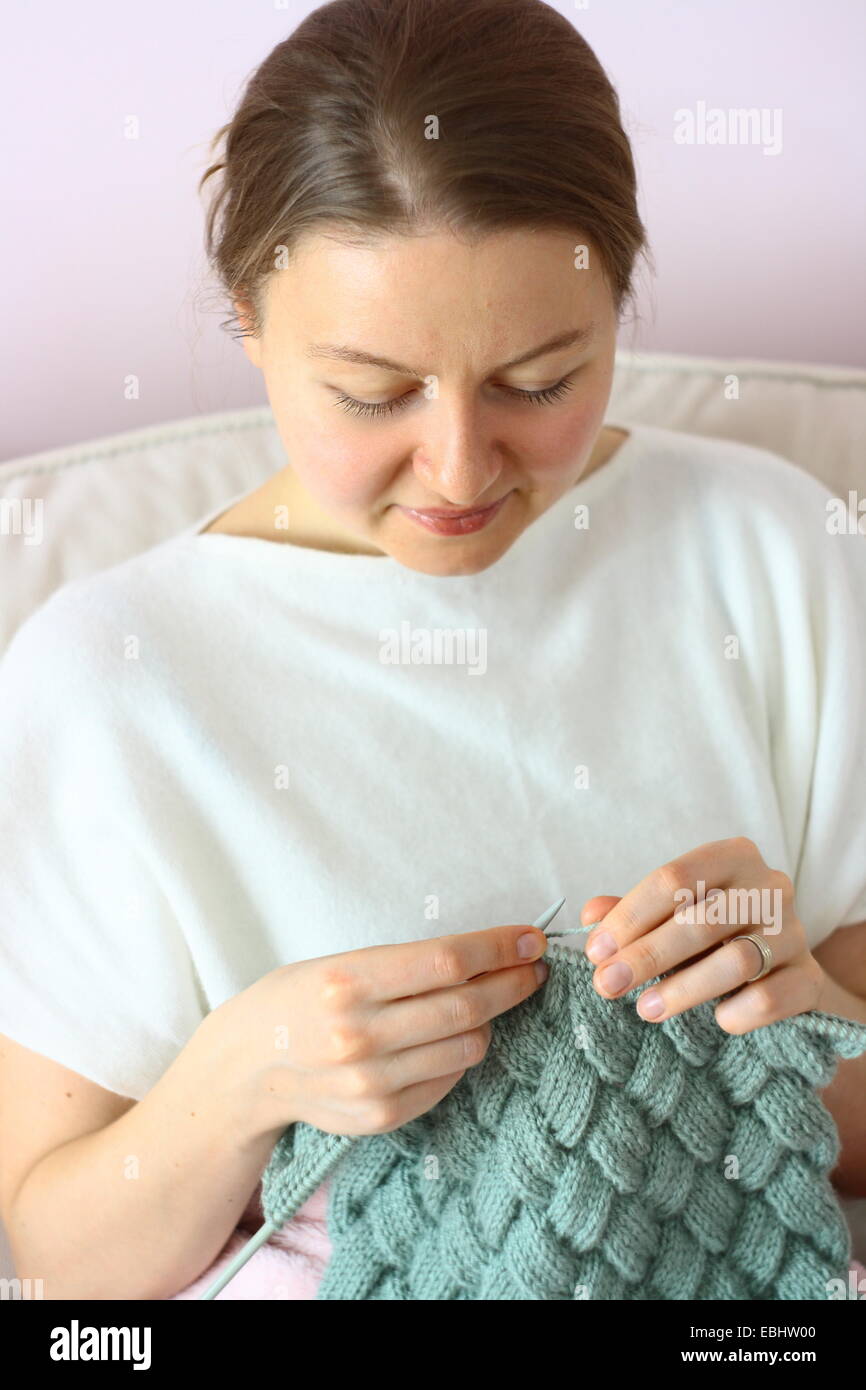happy young woman knitting on sofa Stock Photo - Alamy