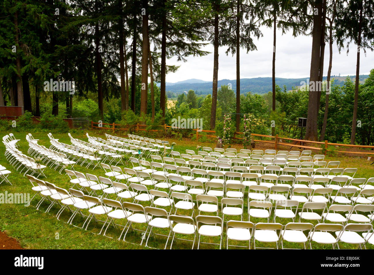 Wedding ceremony at an outdoor venue with grass, trees, and white ...