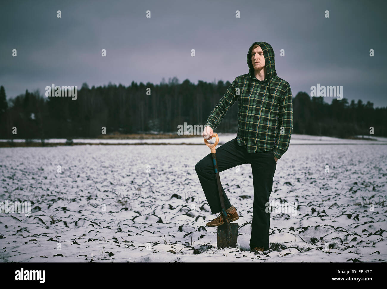 Handsome young man and shovel, snowy plowed field on background - cross ...