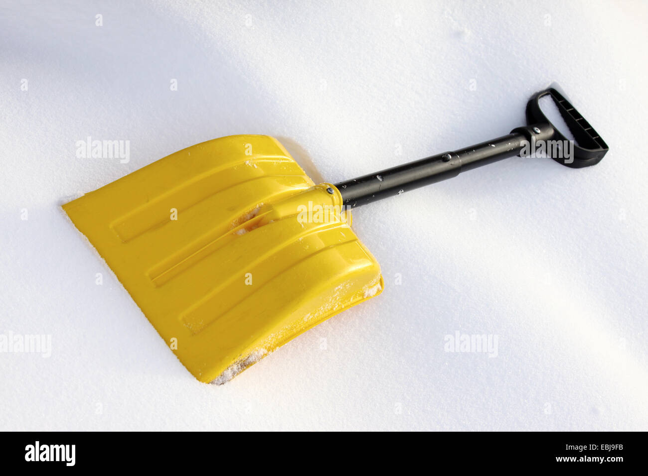 Yellow snow shovel lying on the snow Stock Photo - Alamy