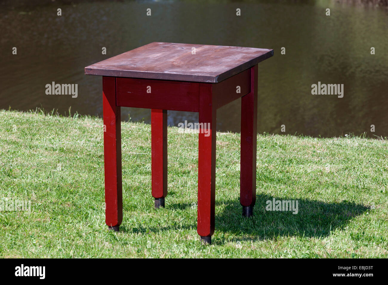 Red wooden table in a meadow, background water Stock Photo - Alamy