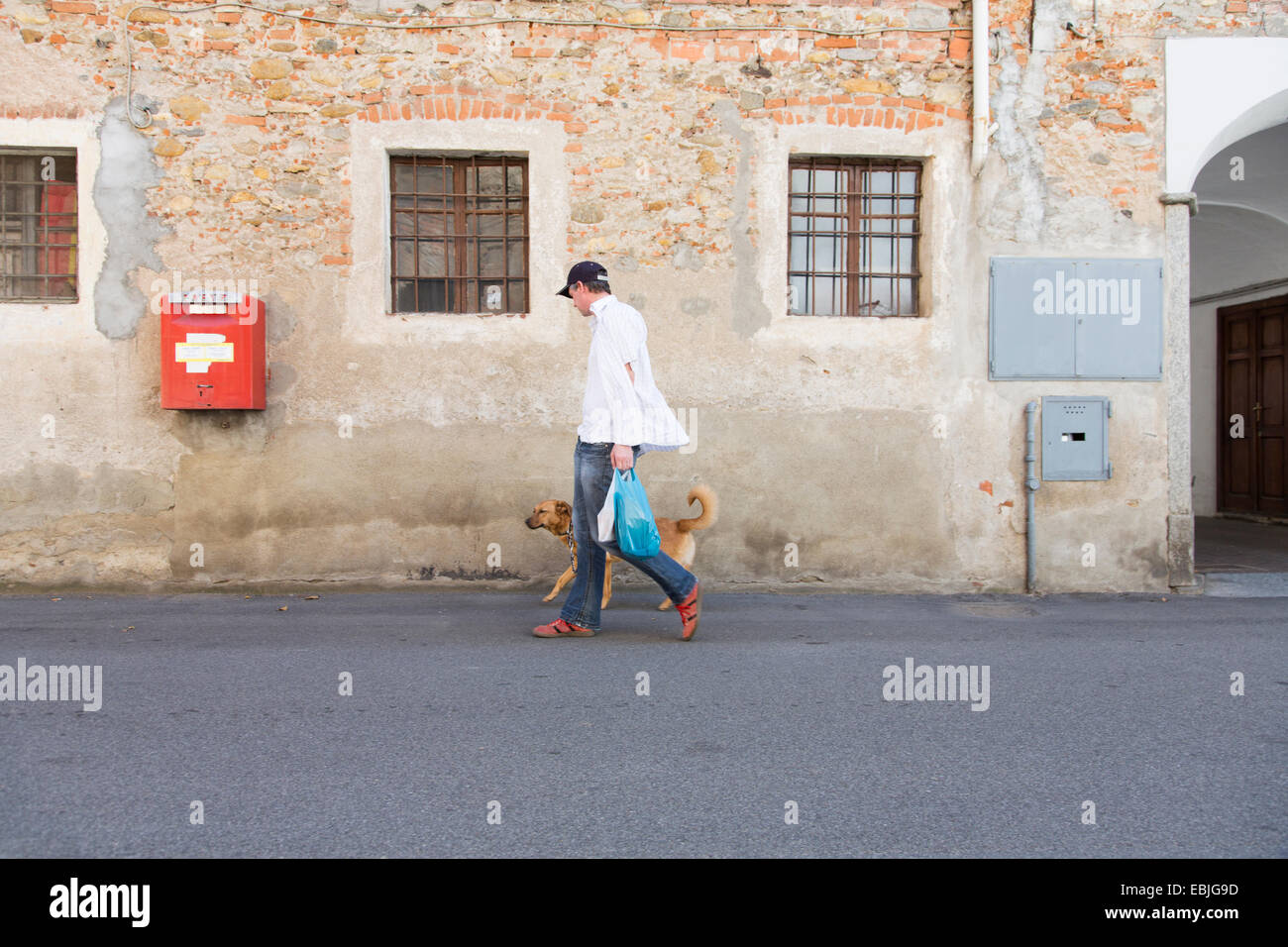 Man walking dog on street, Suno, Novara, Italy Stock Photo - Alamy