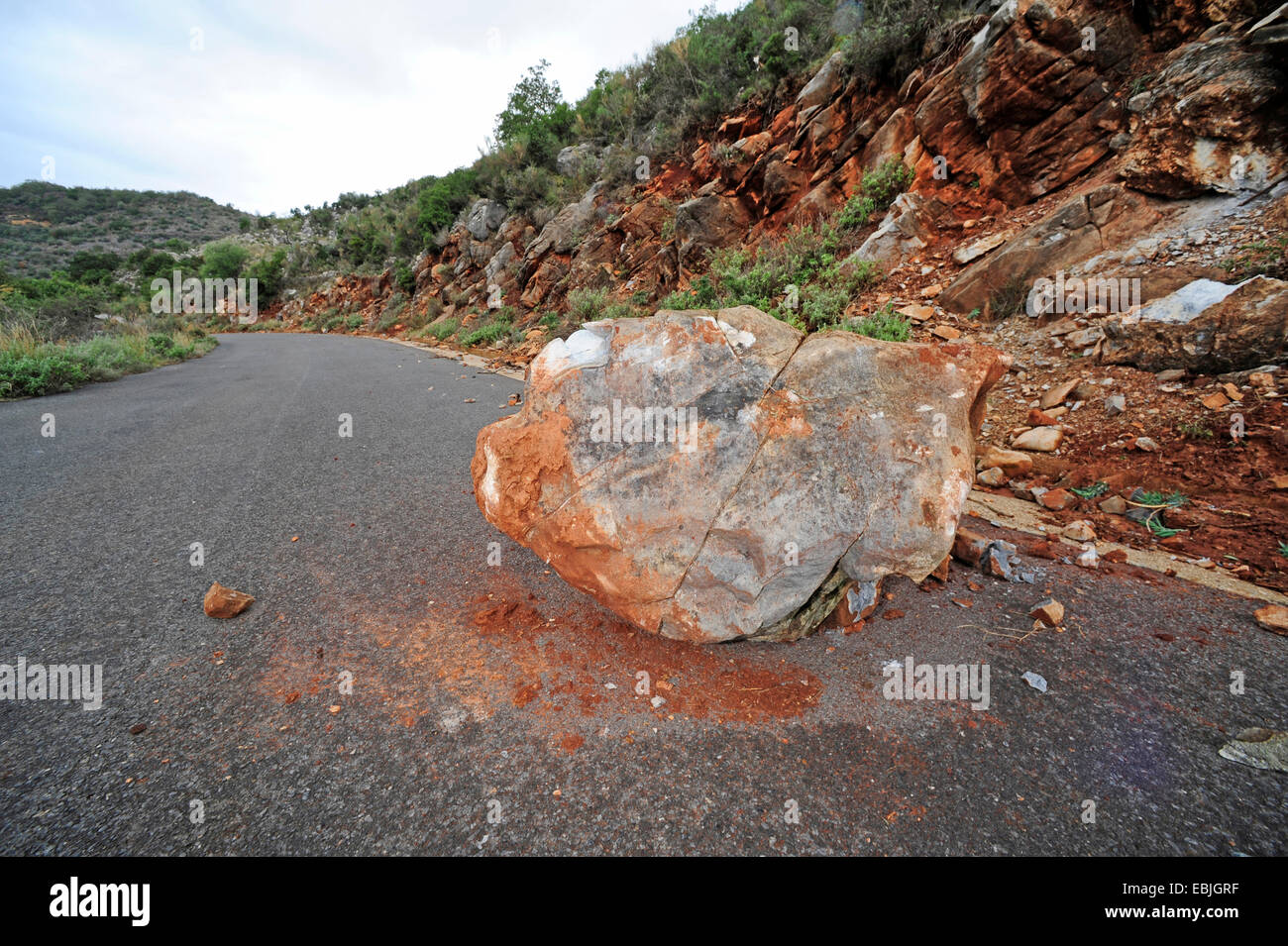 boulder lying on a country road after an earthquake with landslide ...