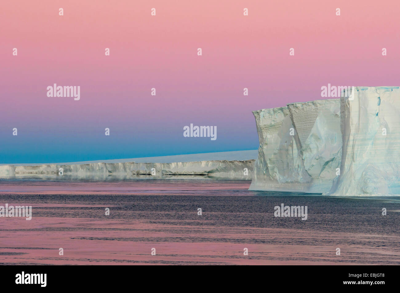 red morning sky over the edge of a table iceberg near the iceberg ...