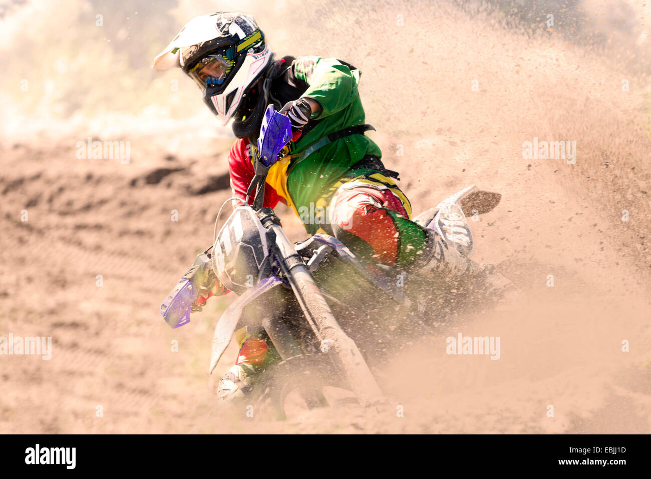 Young male motocross rider racing and leaning into mud track Stock ...