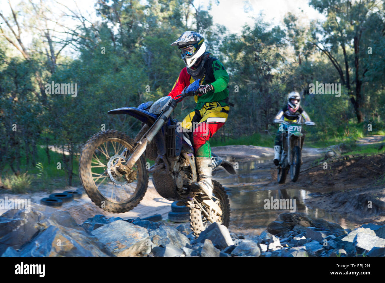 Two young male motocross riders racing through forest river Stock Photo ...