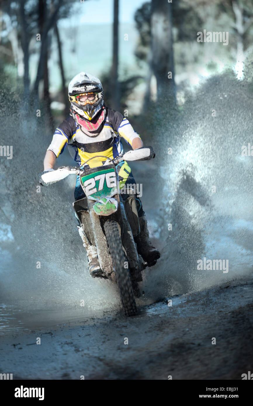 Young male motocross racer splashing through forest puddle Stock Photo ...