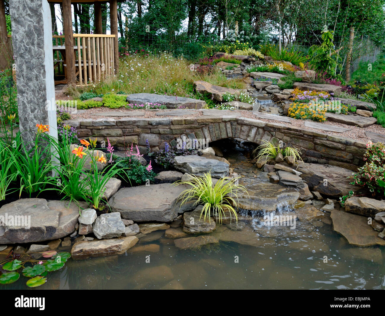 A sandstone rock and water feature with a stone bridge and waterfalls ...