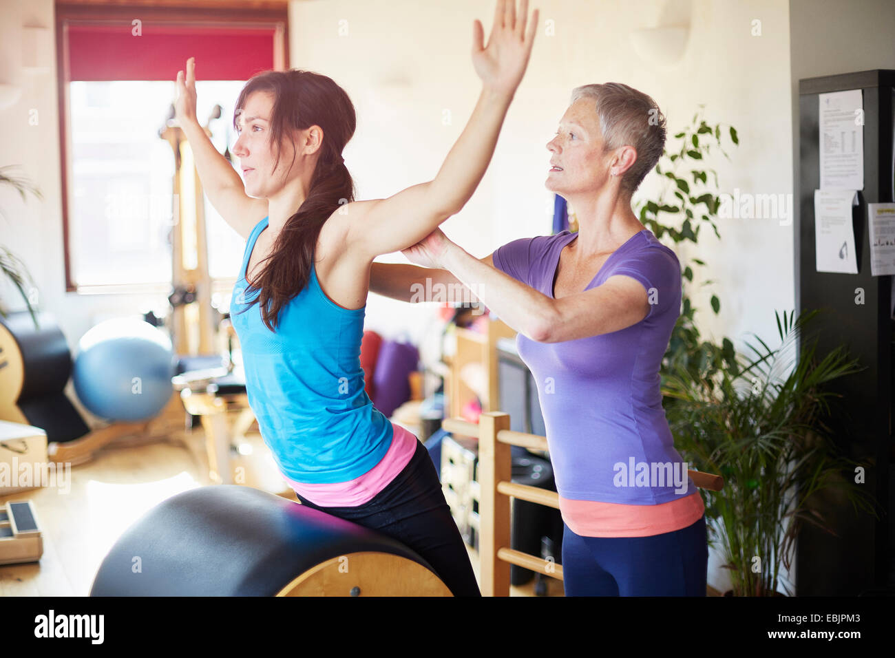Female student leaning forward onto pilates barrel in pilates gym Stock ...