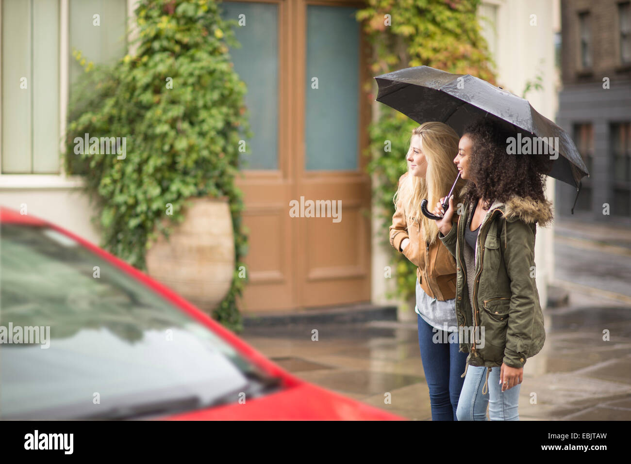Young women using umbrella Stock Photo - Alamy