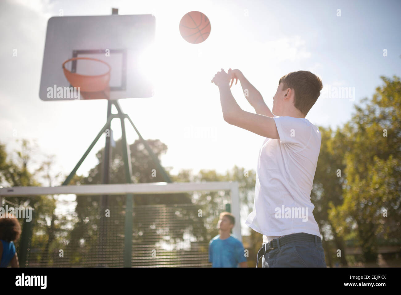 Young male basketball player throwing basketball into hoop Stock Photo ...