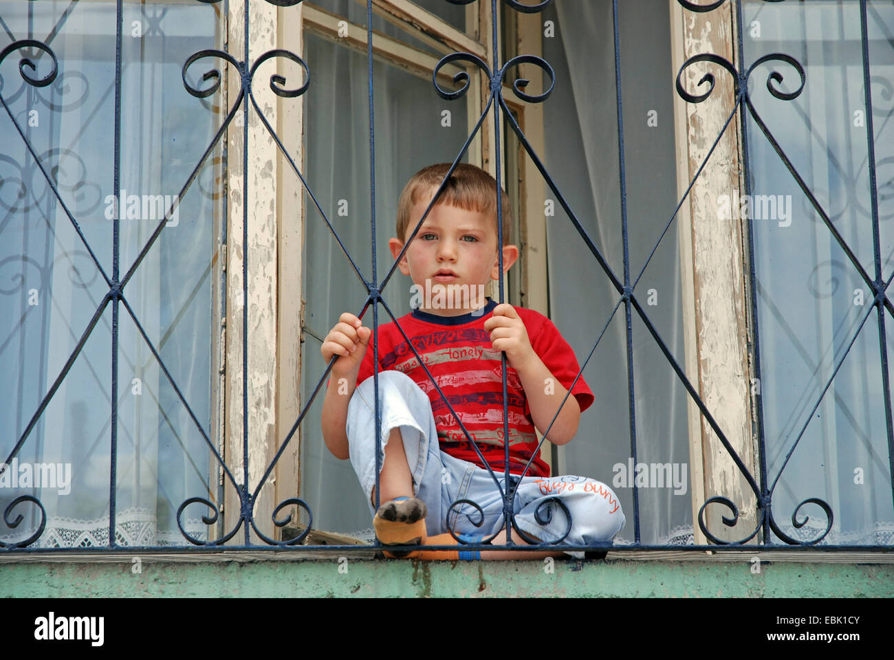 boy sitting at opened window, viewing through grid, Turkey, Erzurum ...