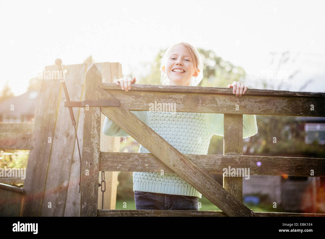 Girl looking over wooden gate Stock Photo - Alamy