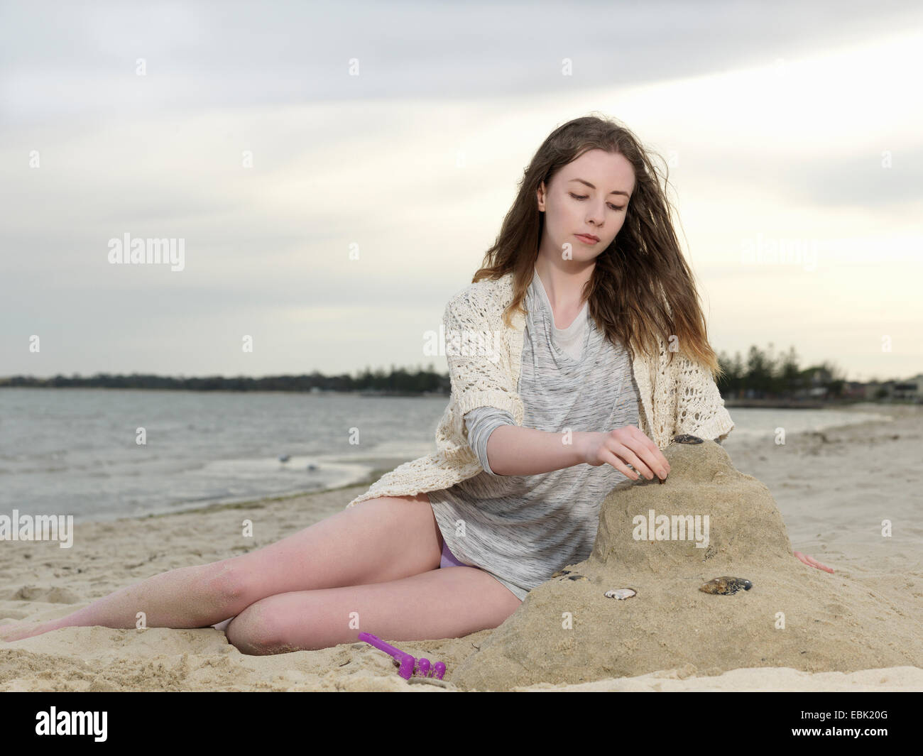 Young woman building sandcastle Stock Photo - Alamy