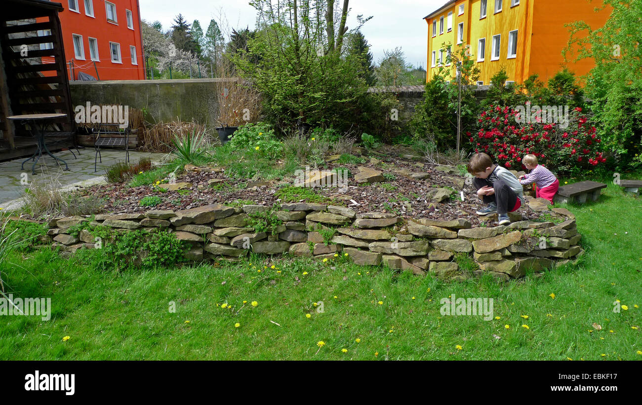 two little boys watching insects in a rock garden Stock Photo - Alamy