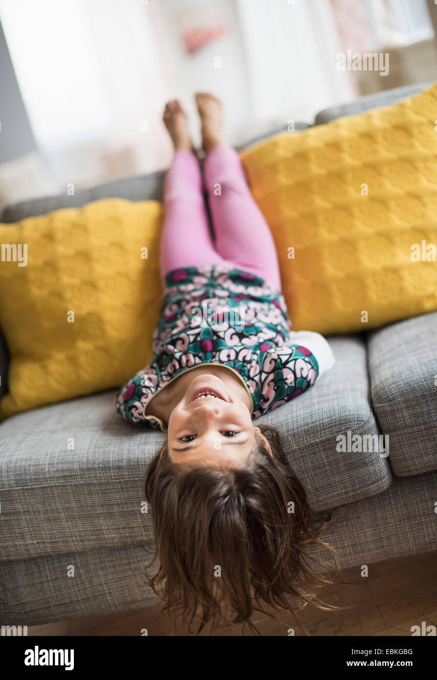 Girl (6-7) lying upside down on sofa Stock Photo - Alamy