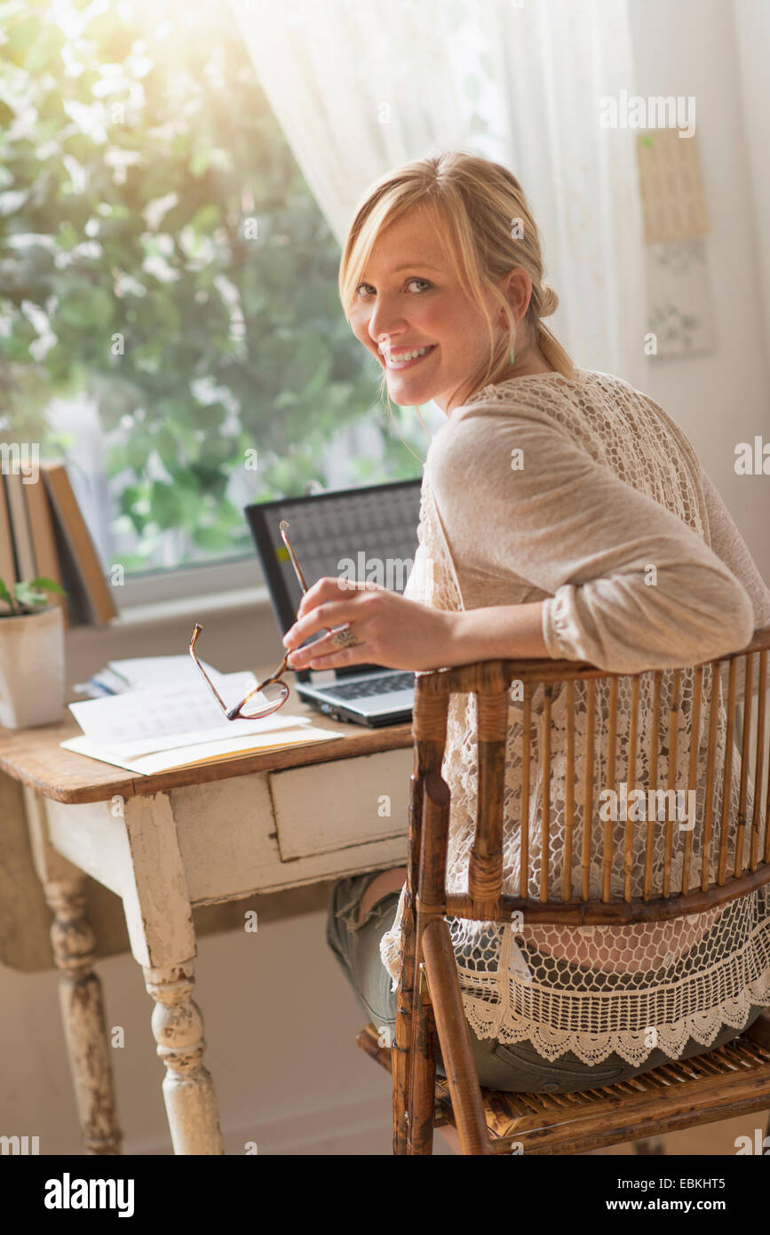 Smiling woman sitting at desk and looking over shoulder Stock Photo - Alamy