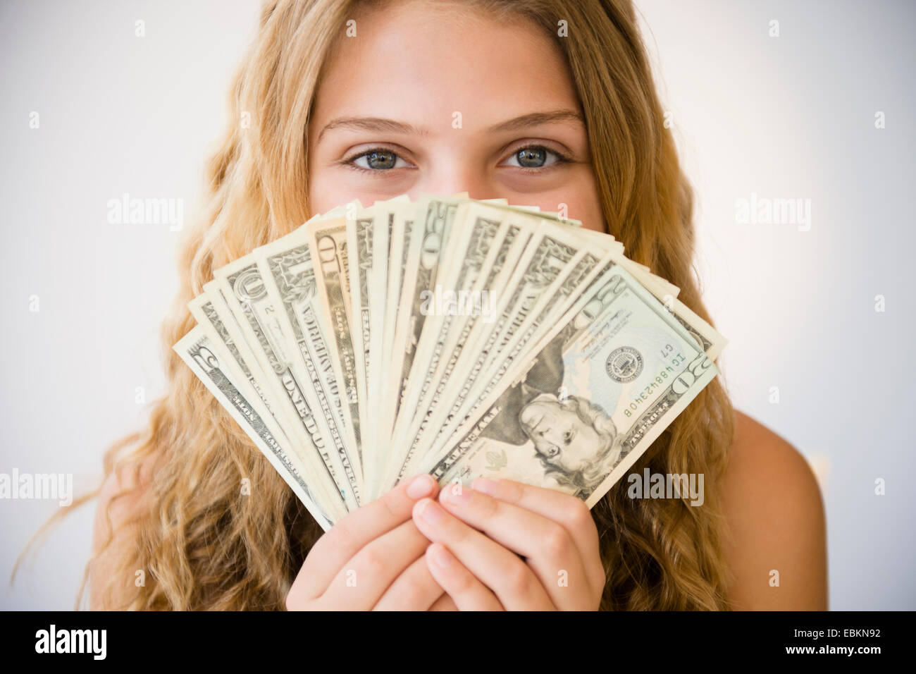 Girl (12-13) holding money fan against her face Stock Photo - Alamy