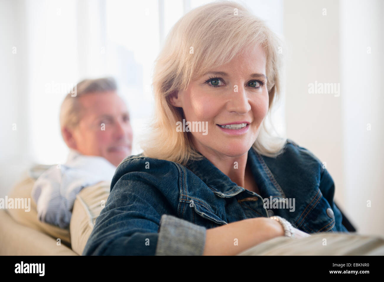 Portrait of woman wearing denim jacket sitting on sofa Stock Photo - Alamy