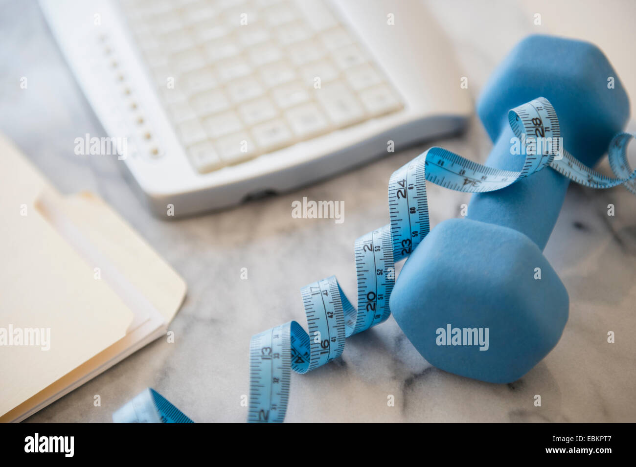 Studio shot of weight, measuring tape, files and computer keyboard ...