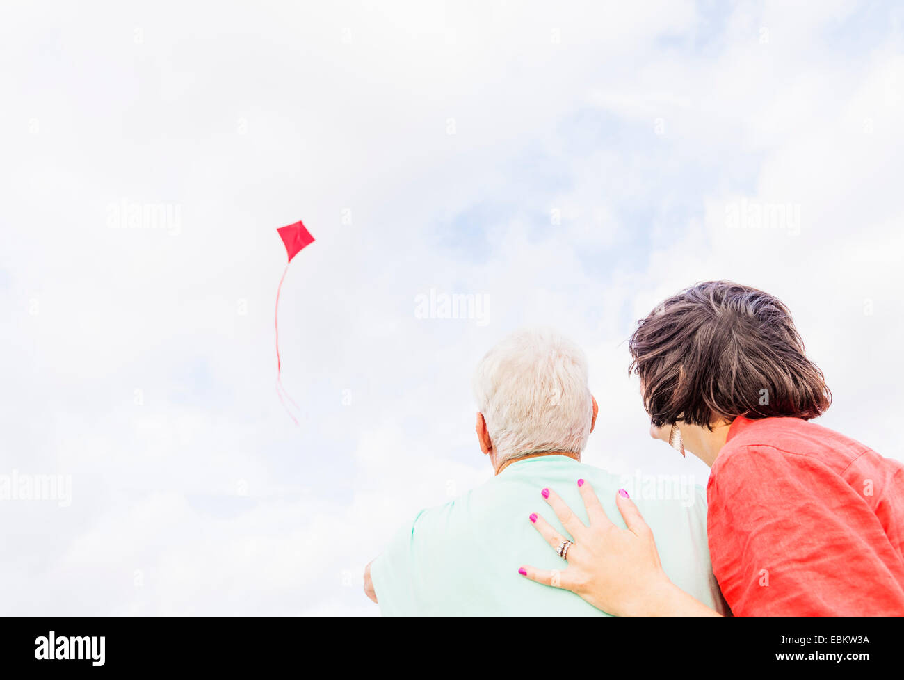 Low-angle view of couple flying kite together Stock Photo - Alamy