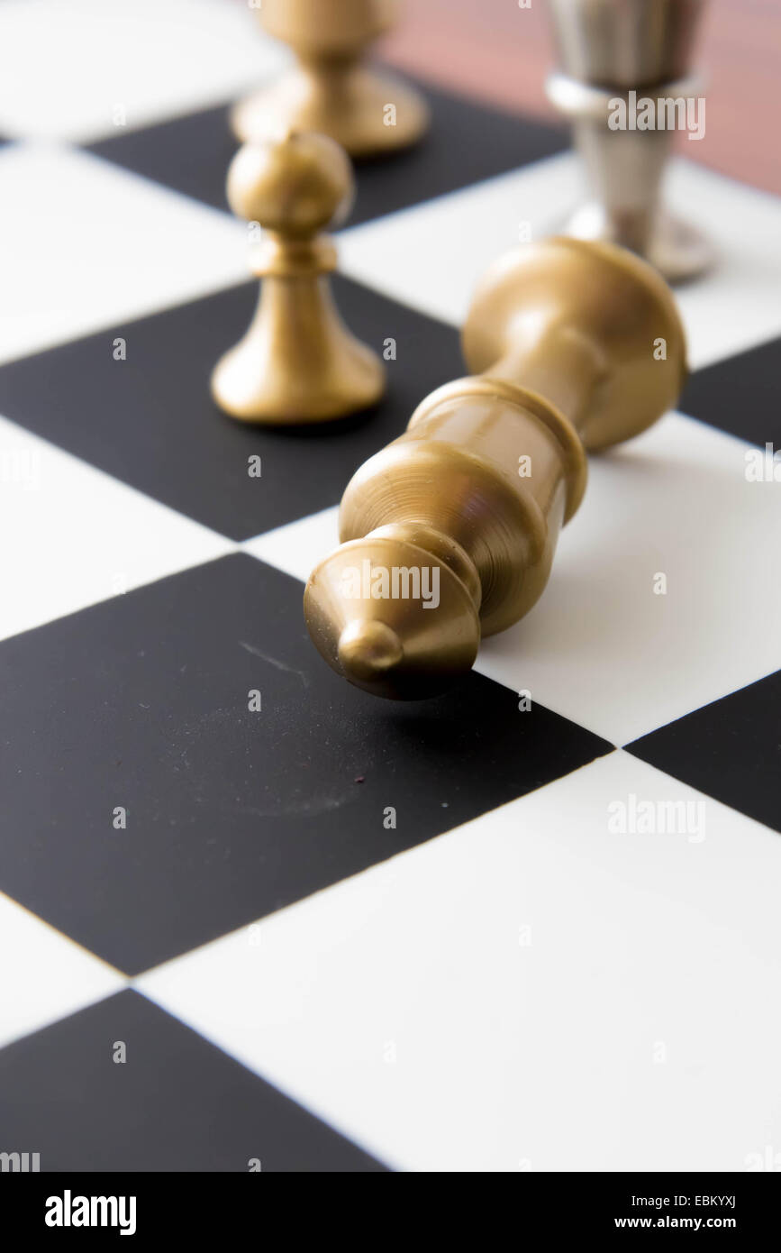 Classic chess game - fallen brass king on chessboard Stock Photo - Alamy