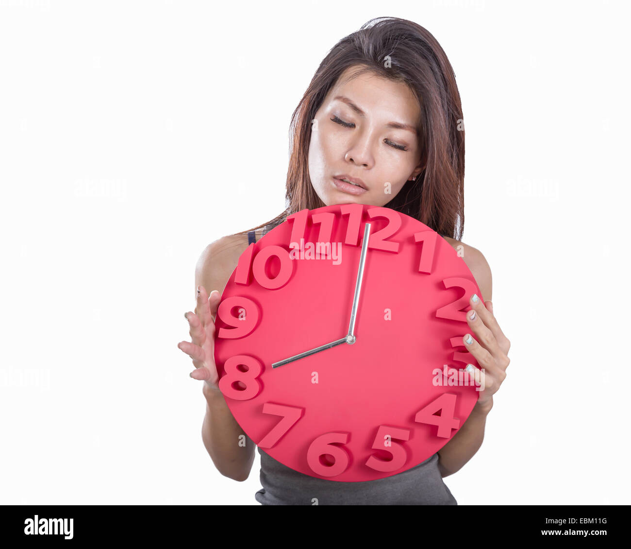 Chinese woman looking tired holding clock showing eight o' clock ...
