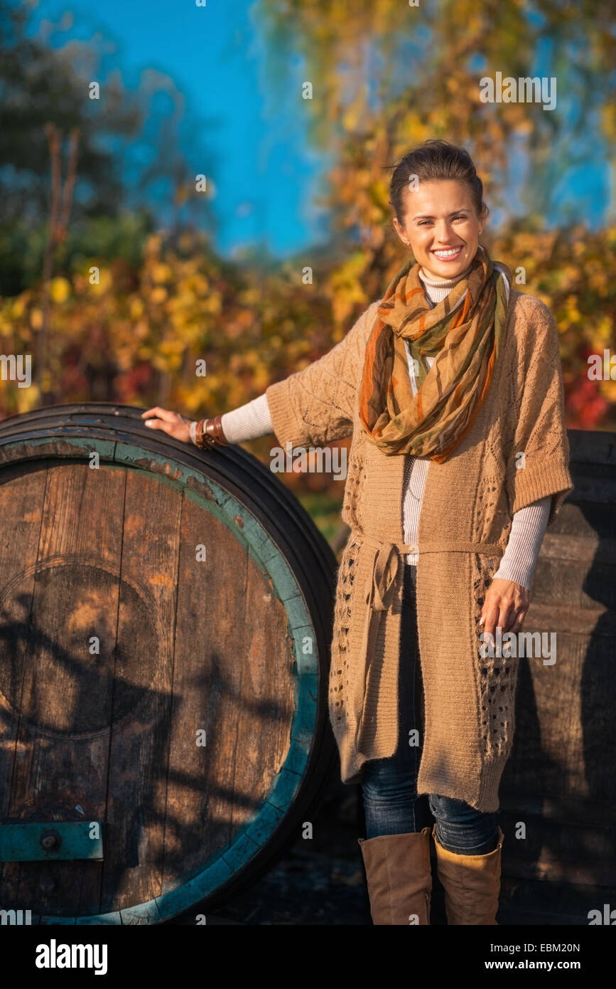 Full length portrait of happy young woman near wooden barrel in autumn ...