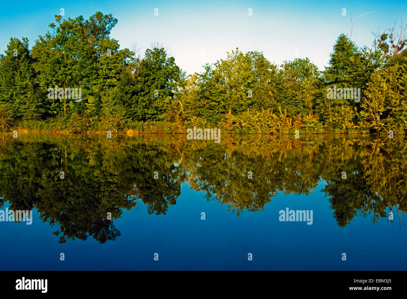 Late summer trees reflecting in the Pakota River, near the Patoka River ...
