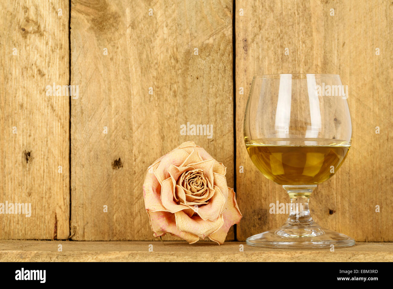 Glass of alcohol and dry rose Stock Photo - Alamy