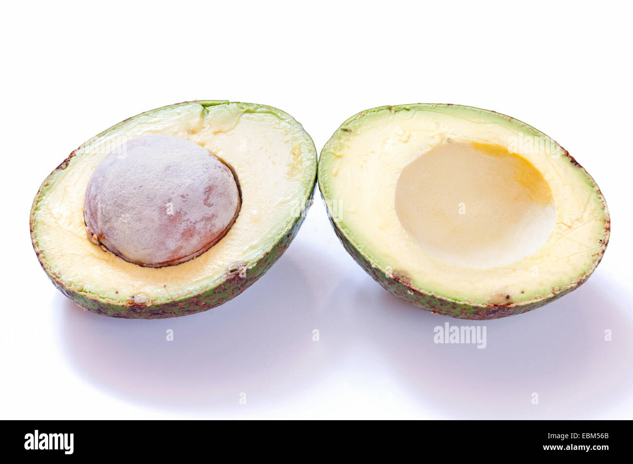 Big green Mexican avocado with seed cut in half on white background ...