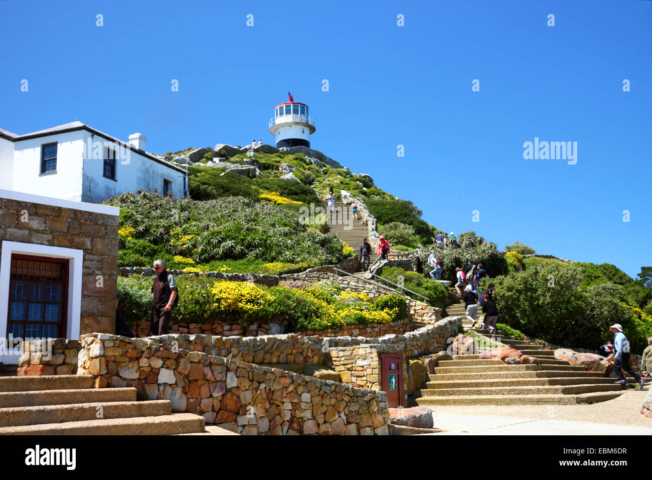 Steps up to a circular lighthouse with buildings in the foreground ...