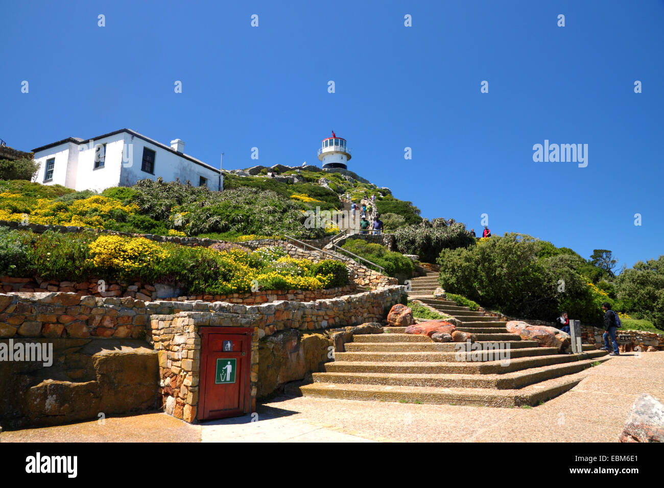 Steps up to a circular lighthouse with buildings in the foreground ...