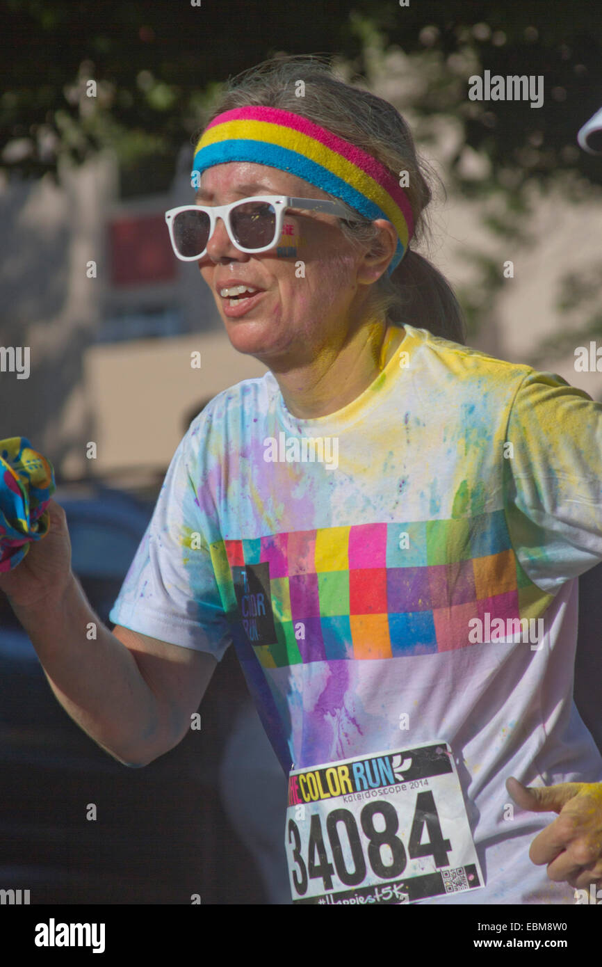 A colorful, dye splatted woman runs in the Asheville 5K Color Run race ...