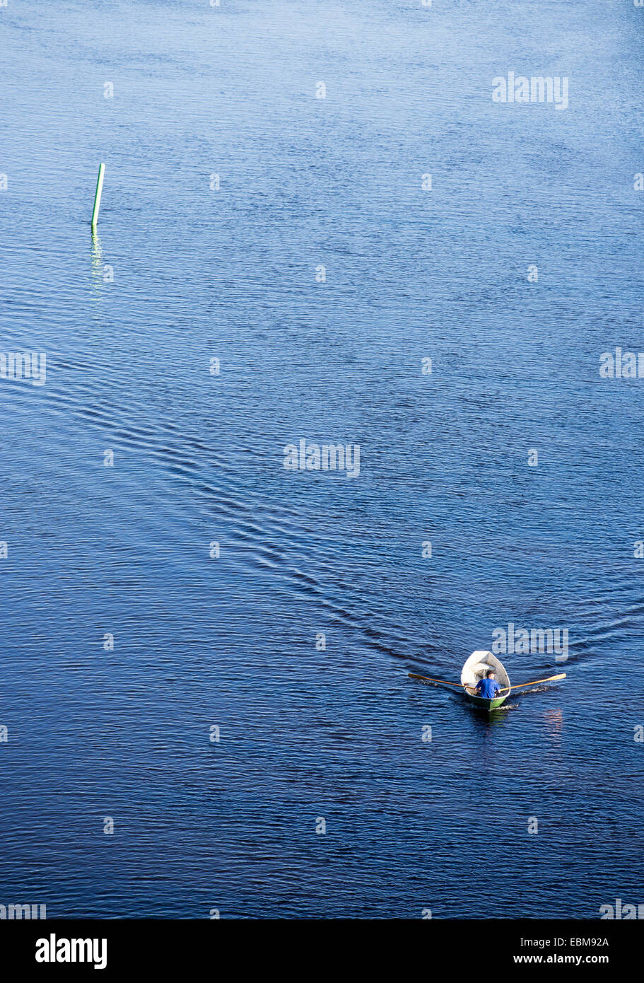 Aerial view of a man rowing a small fiberglass rowboat / skiff / dinghy ...