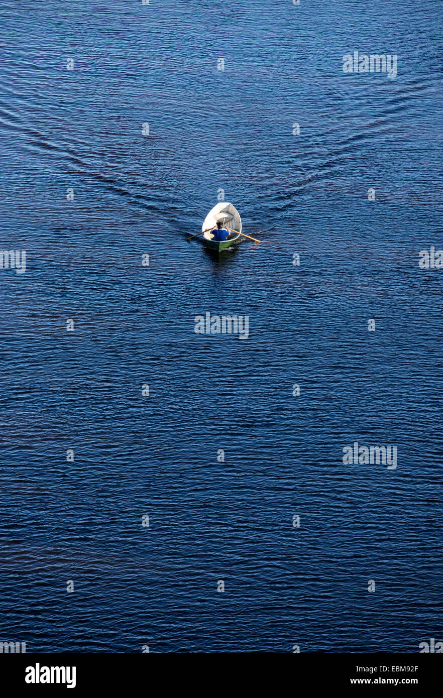 Aerial view of a man rowing a small fiberglass rowboat / skiff / dinghy ...