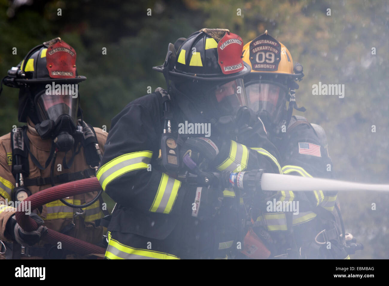 Three firefighters putting out a fire Stock Photo - Alamy