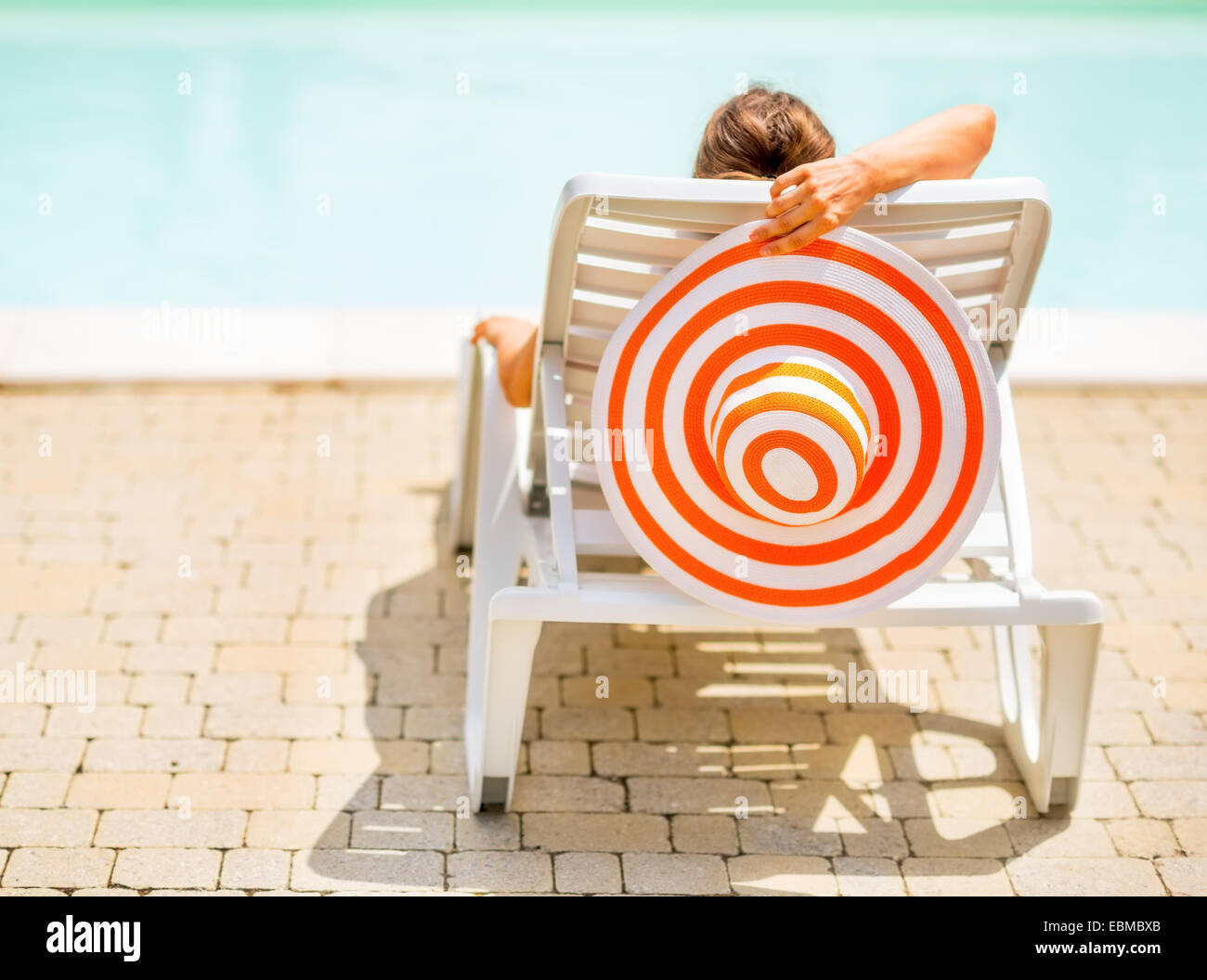 Young woman with hat laying on chaise-longue. rear view Stock Photo - Alamy