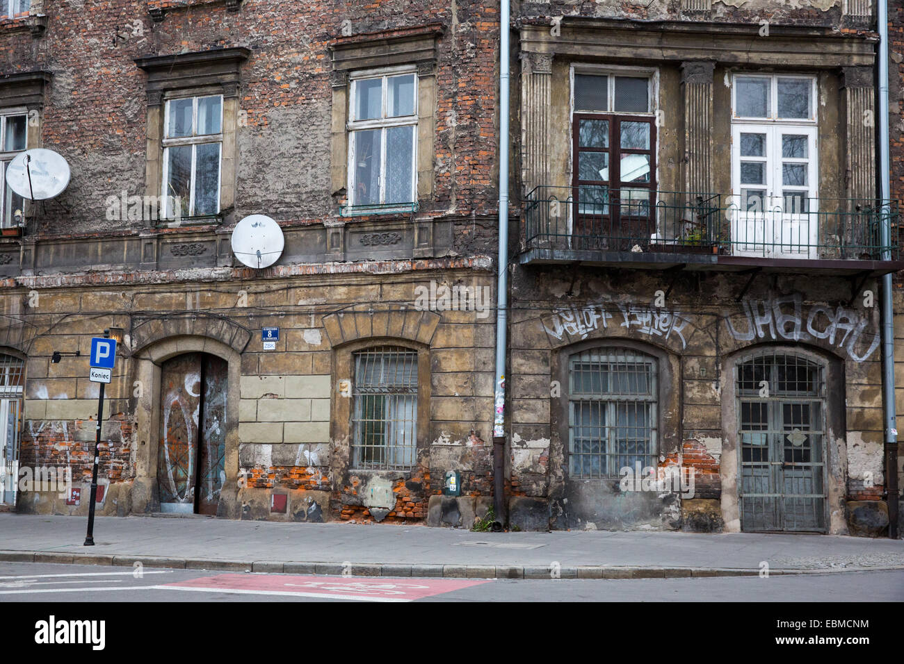 A weathered building facade with satellite dishes and graffiti in ...