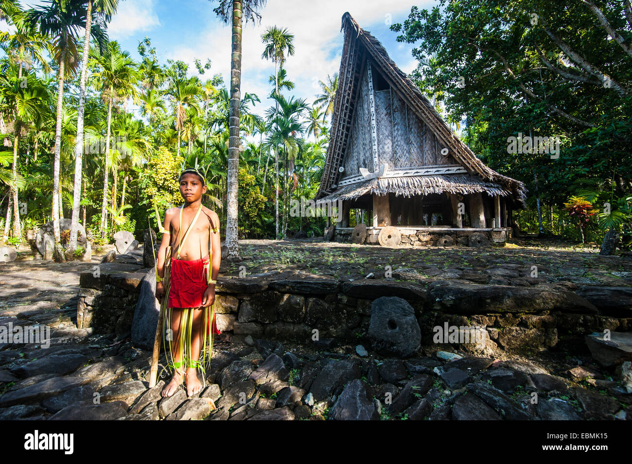 Traditionally dressed boy standing in front of a traditional hut, Yap ...